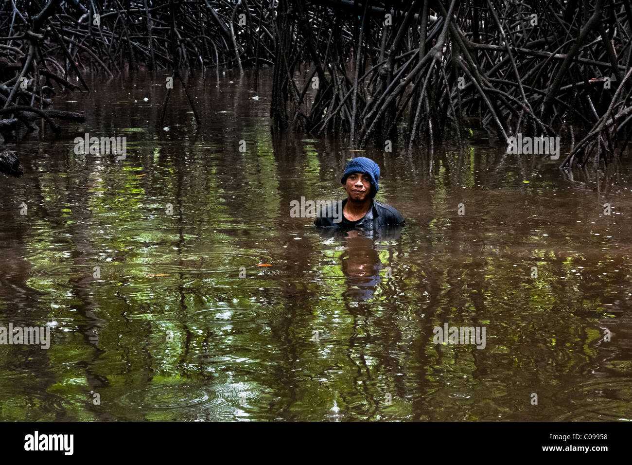 A Colombian boy stands in the water of a shallow channel in the ...