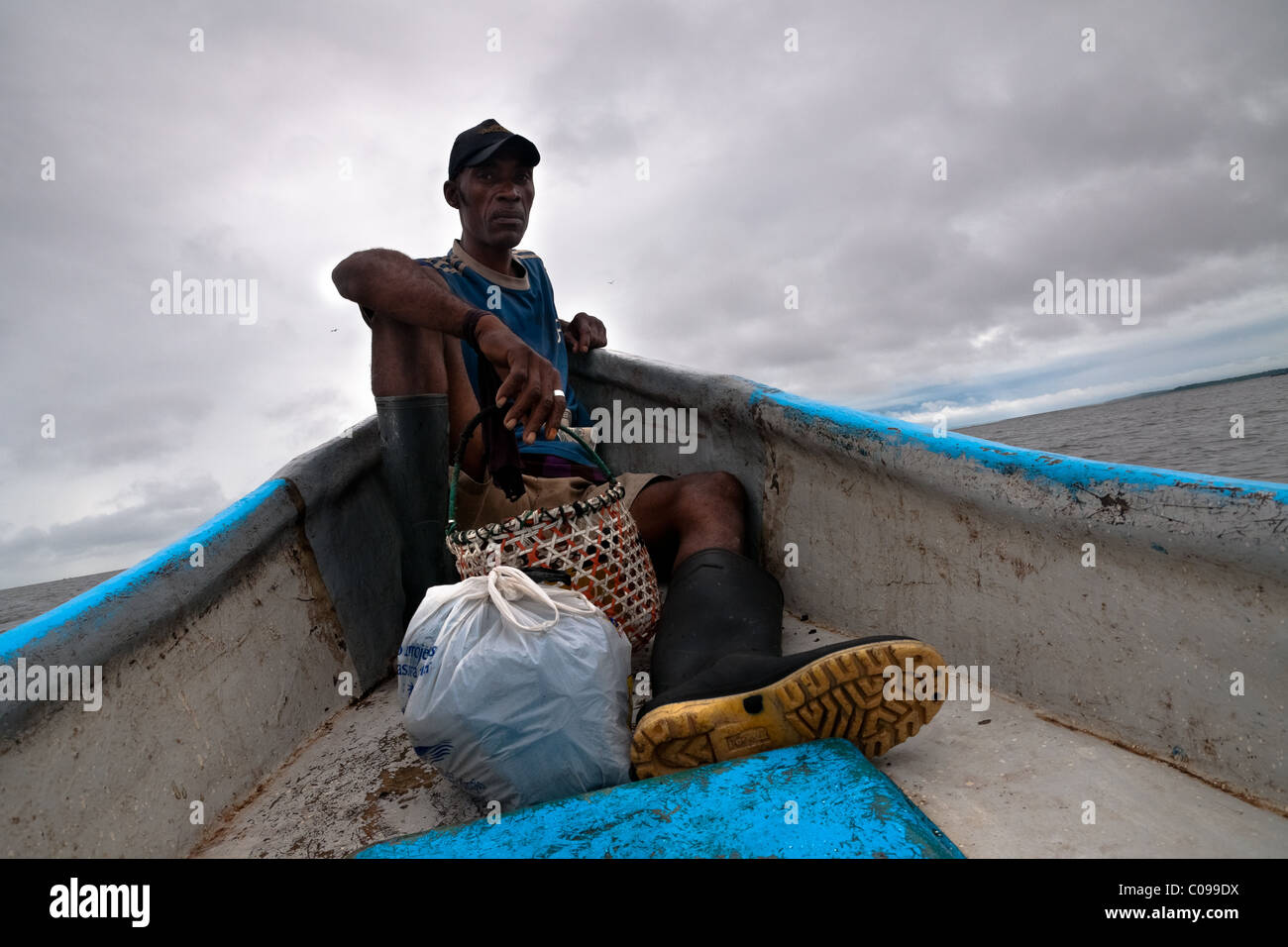 A Colombian shellfish picker sits in the head of a canoe while going to ...