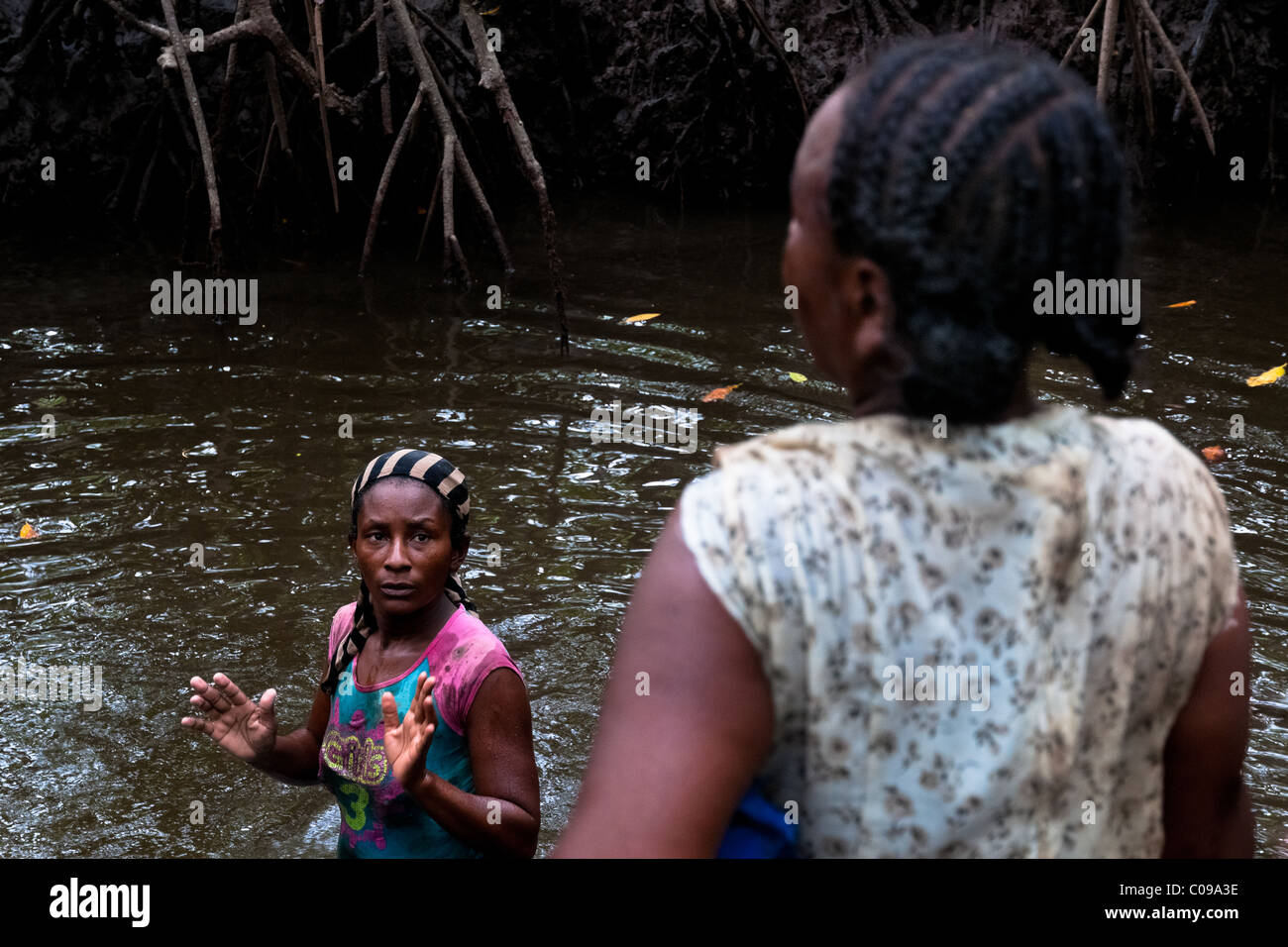 Colombian women wash the mud off their clothes in the dirty water of ...