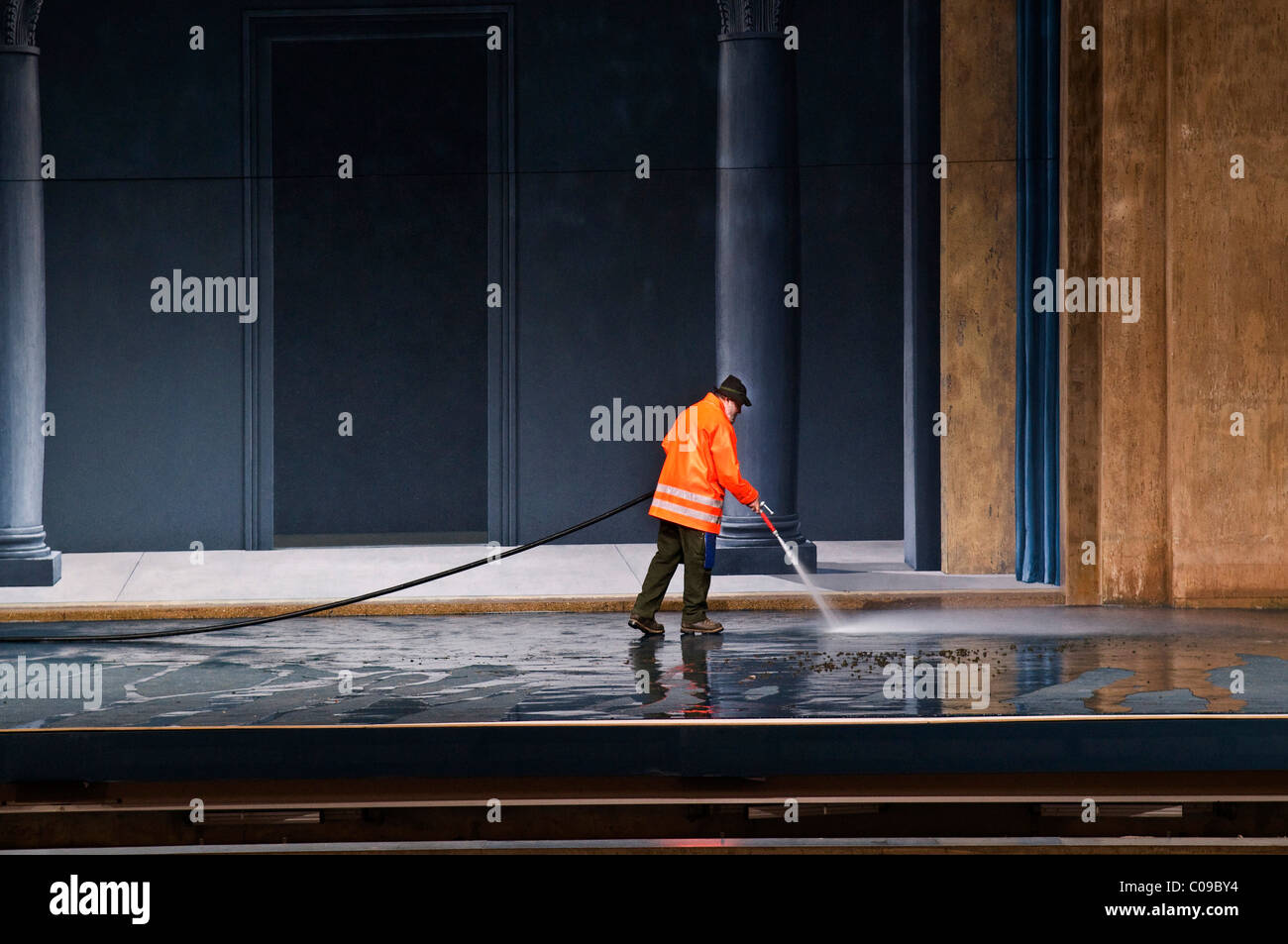 Worker wearing hat and safety jacket cleaning with fire hose, Bavaria ...