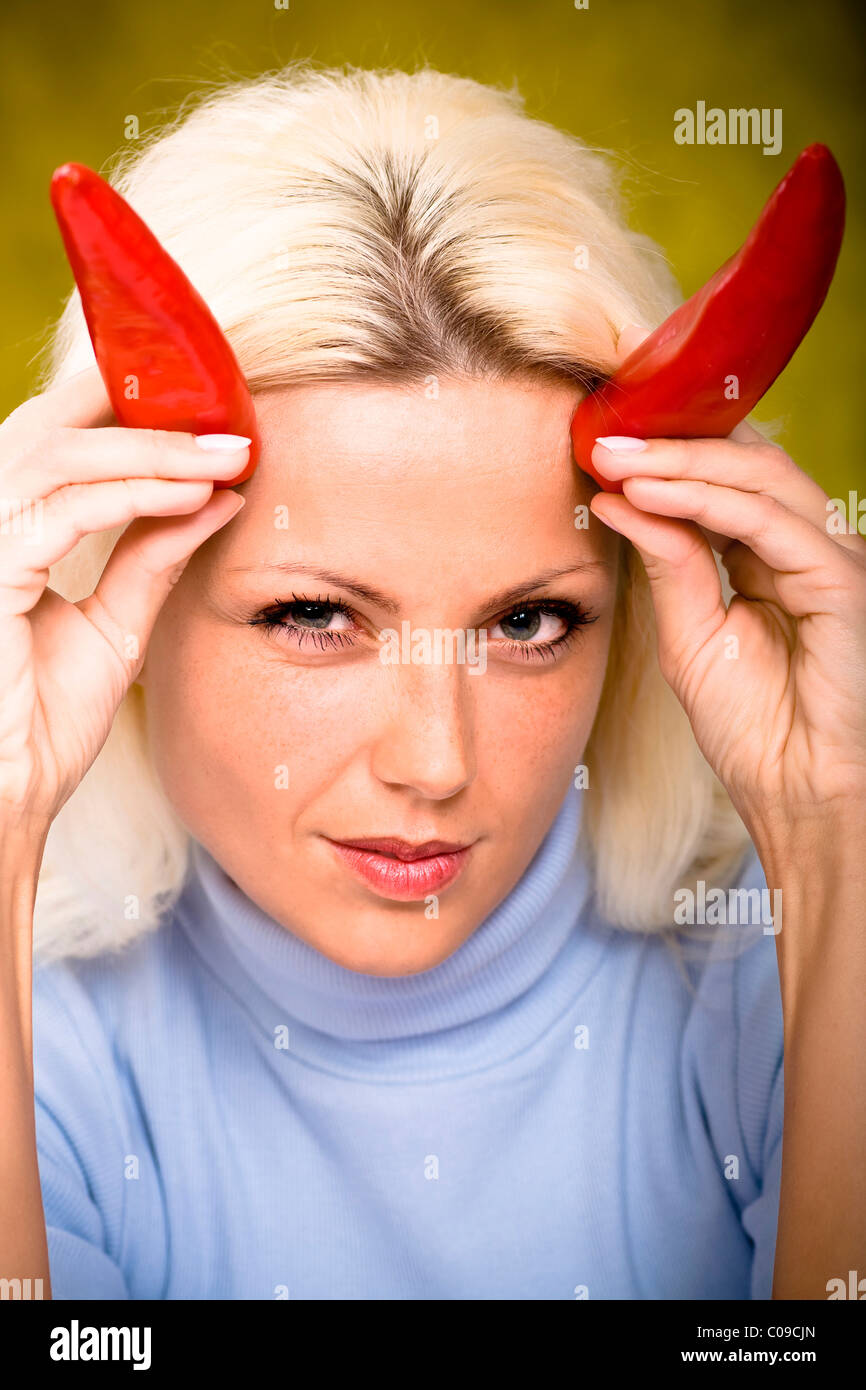 Portrait of a young woman with chilli peppers as horns Stock Photo - Alamy