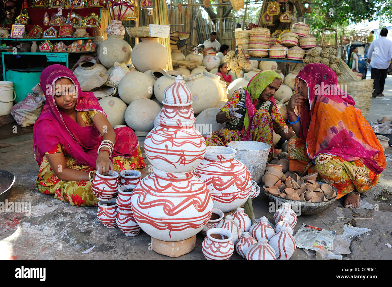 Three women painting pots and water jugs at a pottery stall in Jodhpur ...