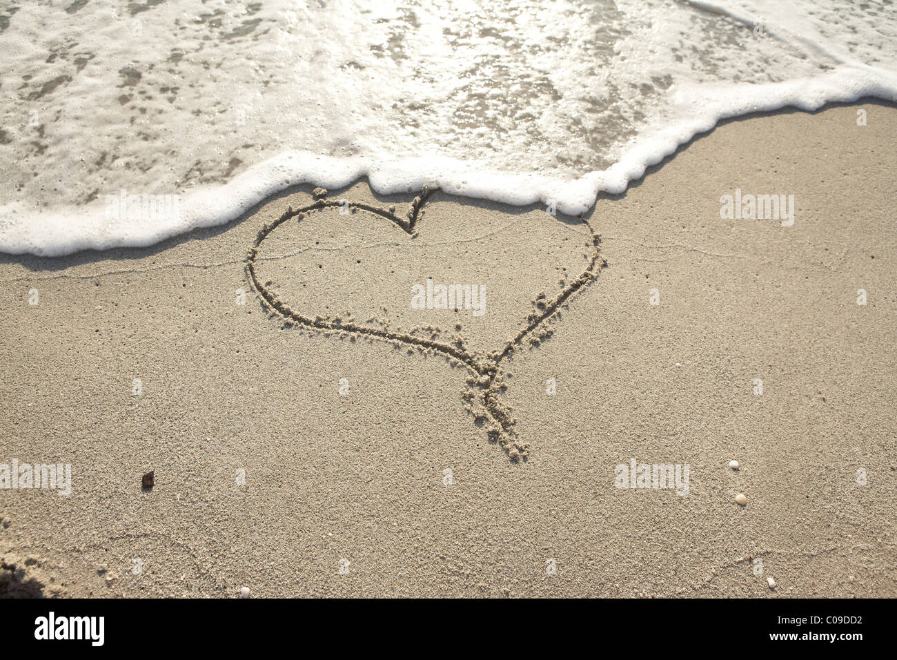 Heart symbol in wet sand being washed away by a wave Stock Photo - Alamy