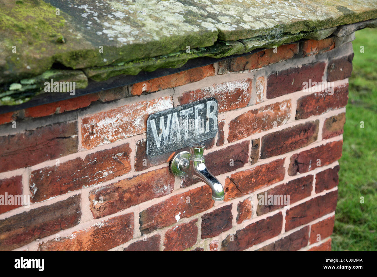An outdoor water tap with a sign saying water on a brick wall Stock ...