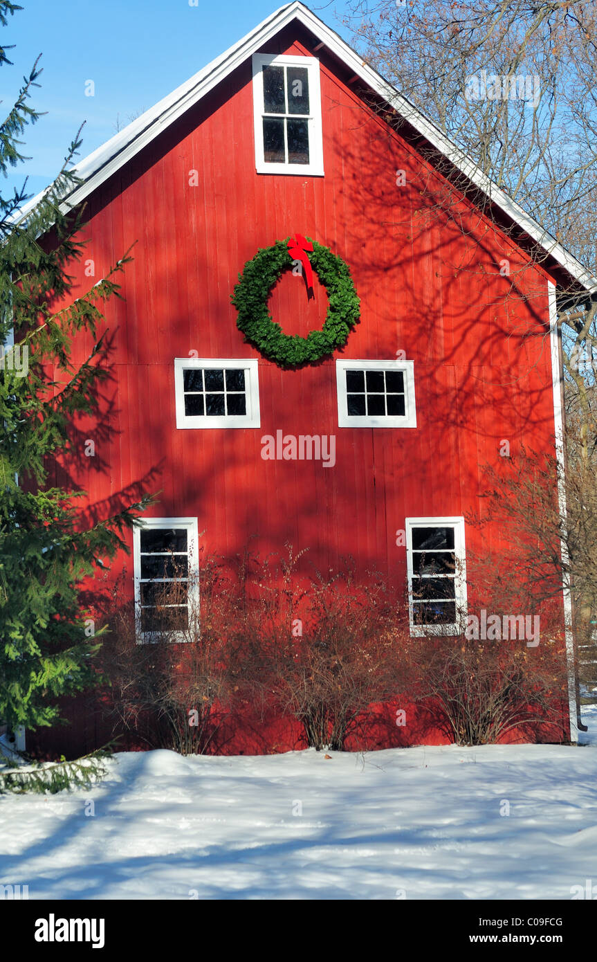 The side of a red barn decorated for the Christmas season on a bright ...