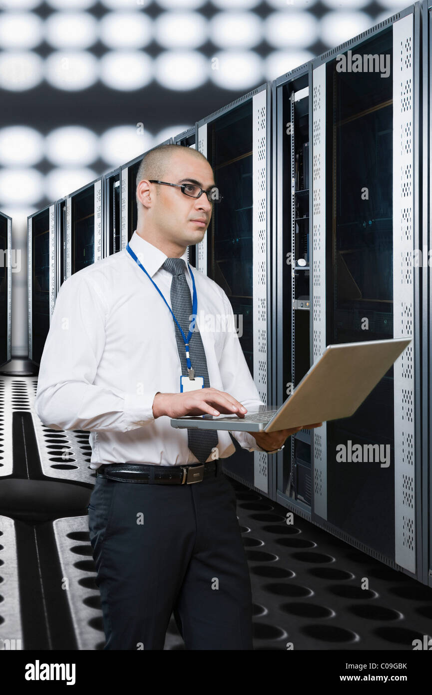 Technician working on a laptop in a server room Stock Photo - Alamy