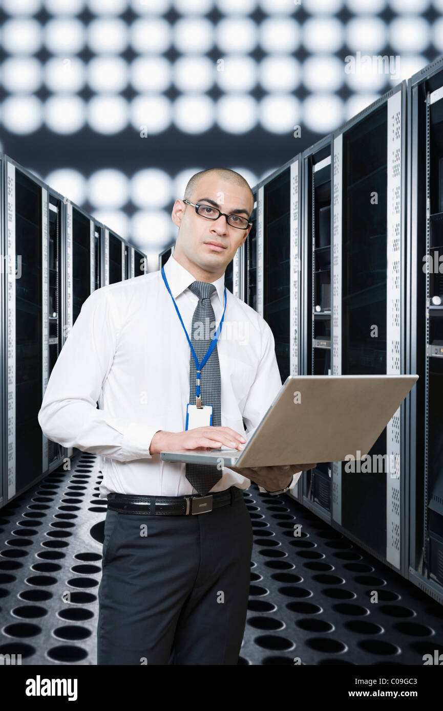Technician working on a laptop in a server room Stock Photo - Alamy