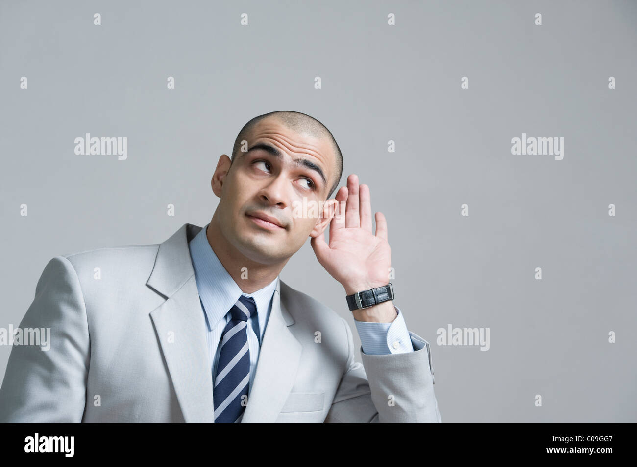 Businessman cupping hand to ear Stock Photo - Alamy