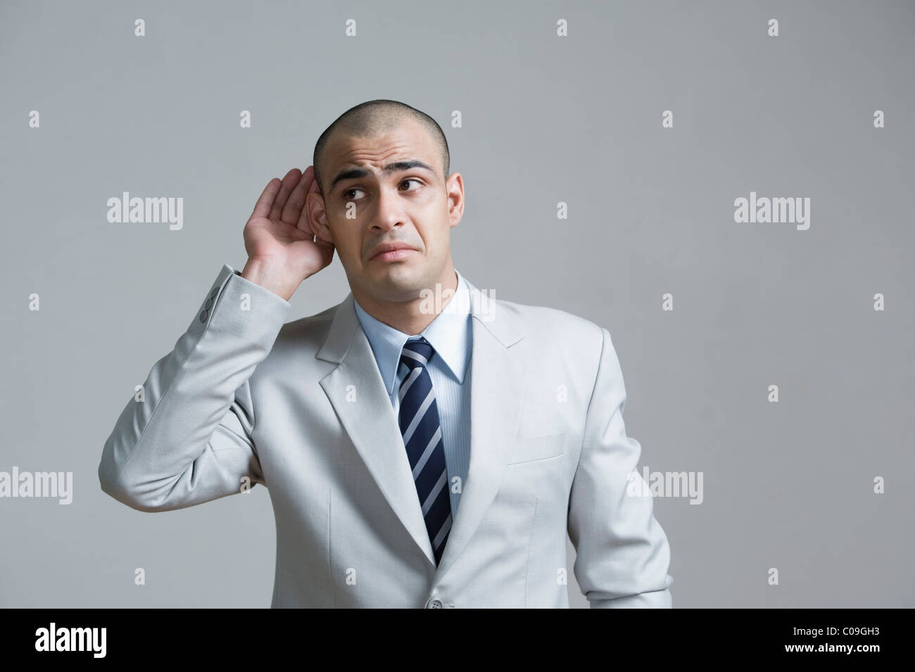 Businessman cupping hand to ear Stock Photo - Alamy