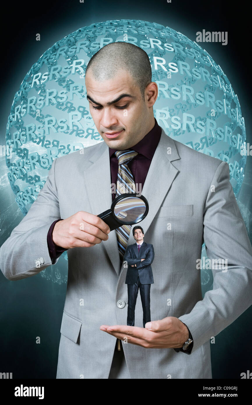 Businessman examining a small man standing on his palm through a ...