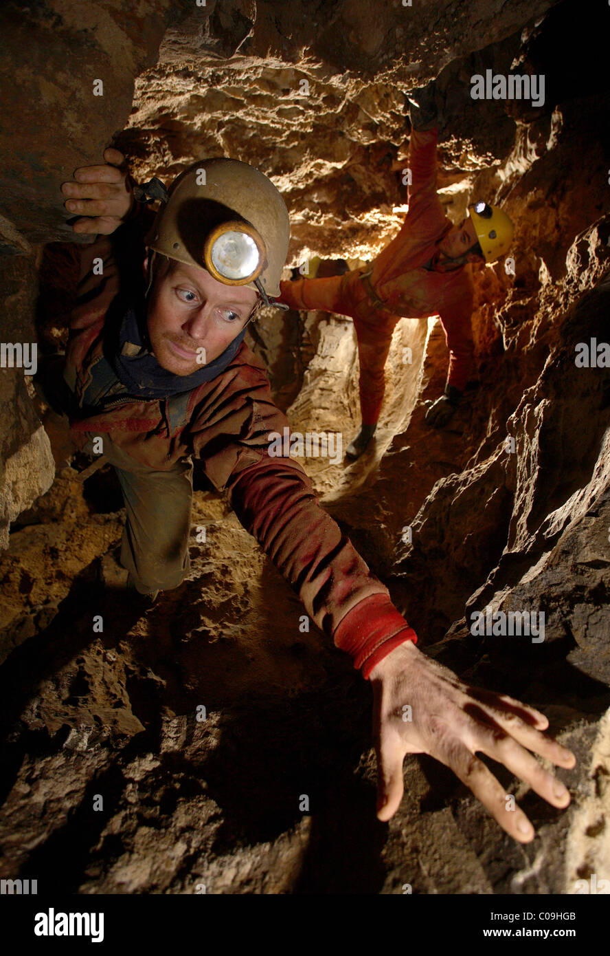 Two male cave explorers climb up through a vertical section deep ...