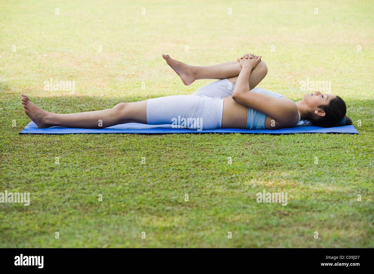 Woman doing Pawanmuktasana (Wind Releasing Pose Stock Photo - Alamy