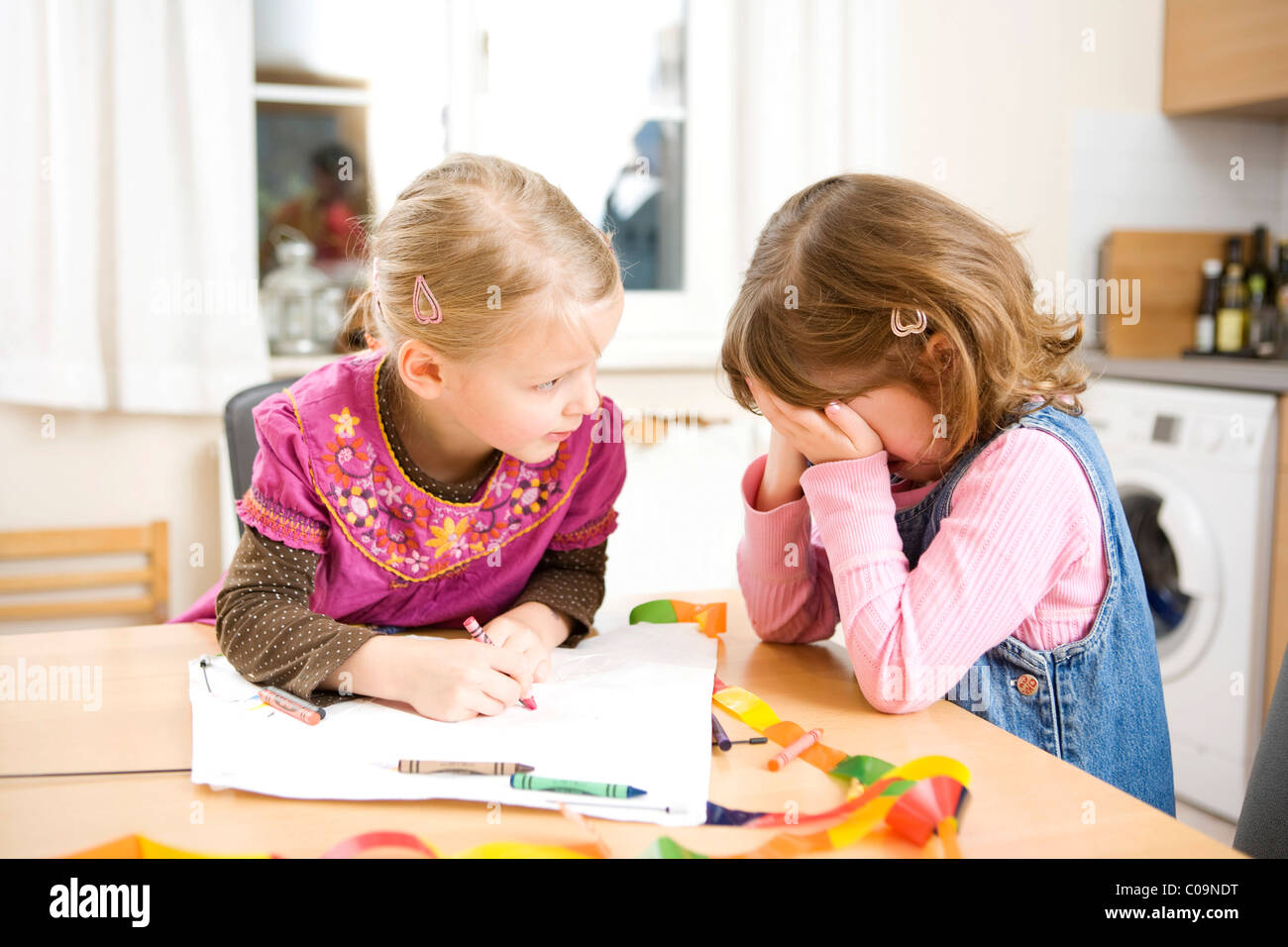 Two girls drawing with wax crayons, one girl crying Stock Photo - Alamy