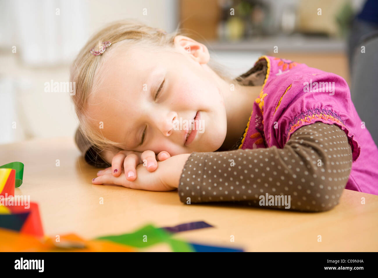 A girl, her head resting on her arms on the table Stock Photo - Alamy