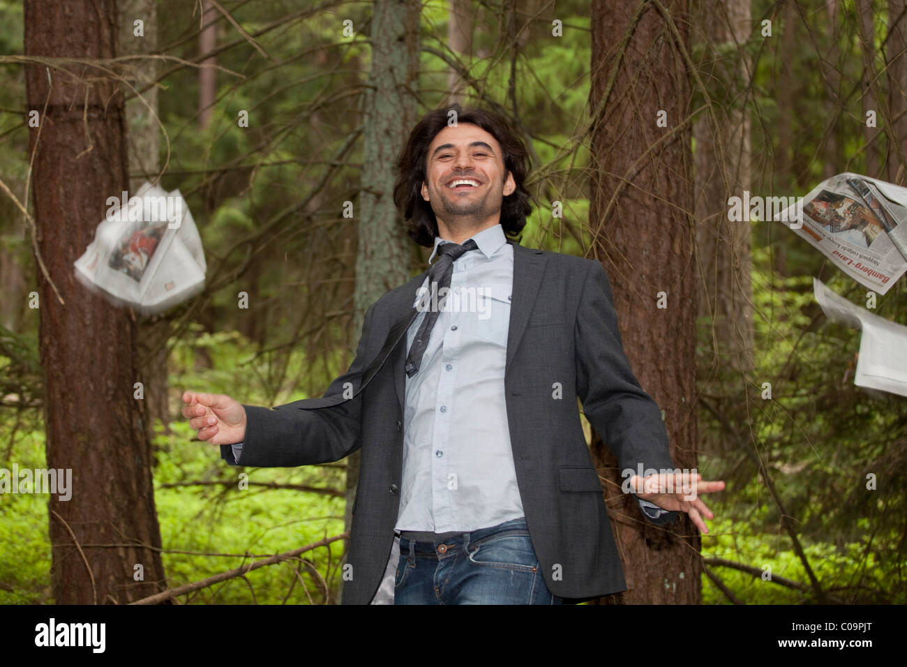 Young smiling businessman throwing around a newspaper in a forest Stock ...