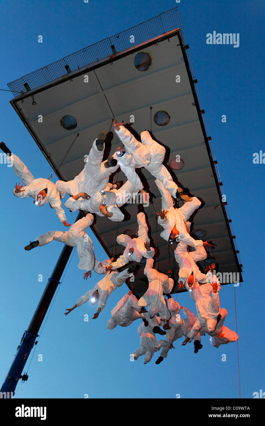 White-clad trapeze artists hanging upside down from a platform in the ...