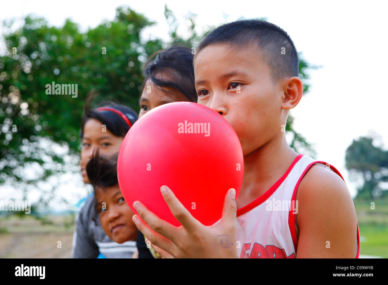 Boy blowing up a red balloon, Margaritha children's home, Marihat ...