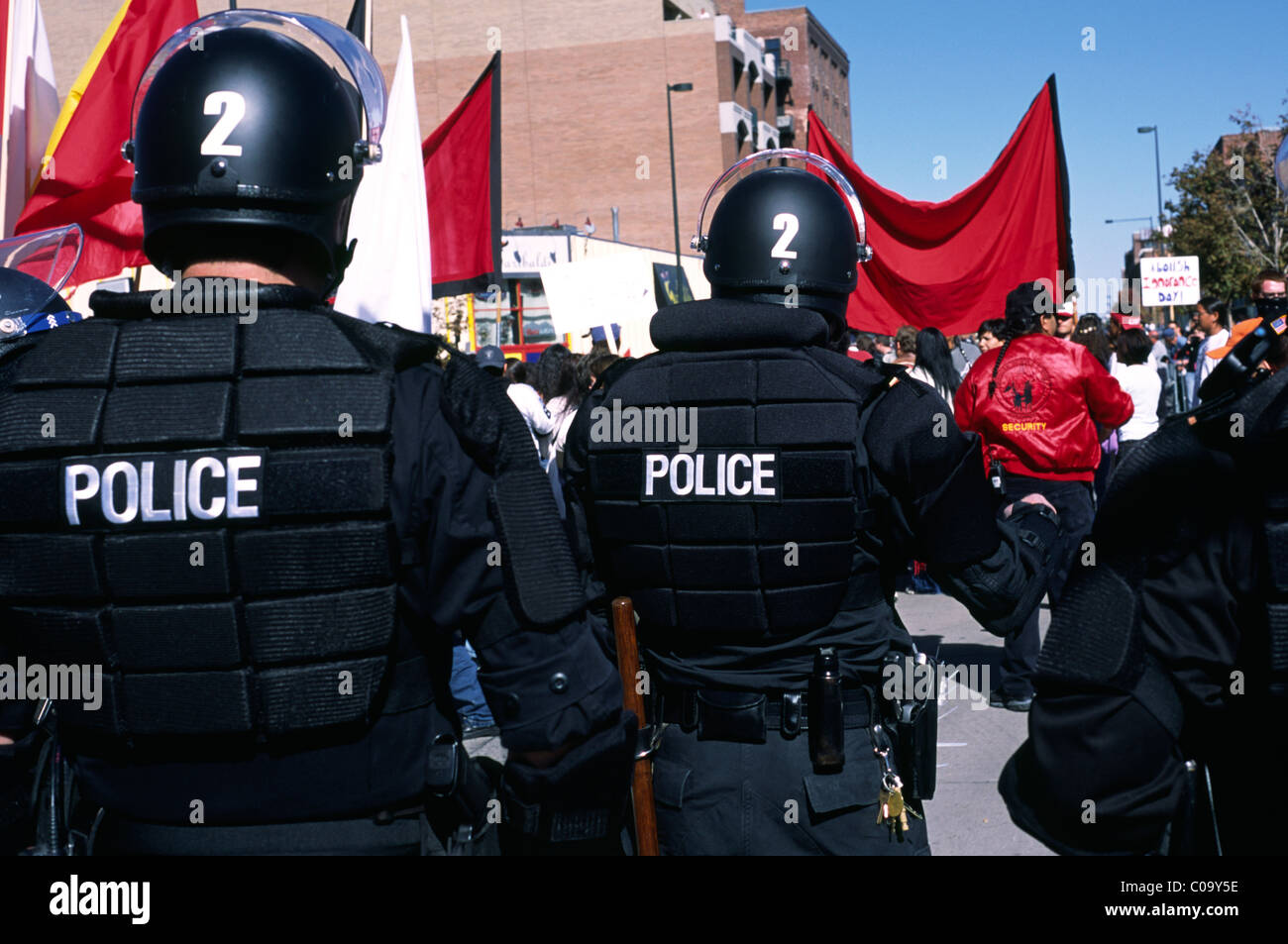Police officers dressed in riot protective clothing stand among ...