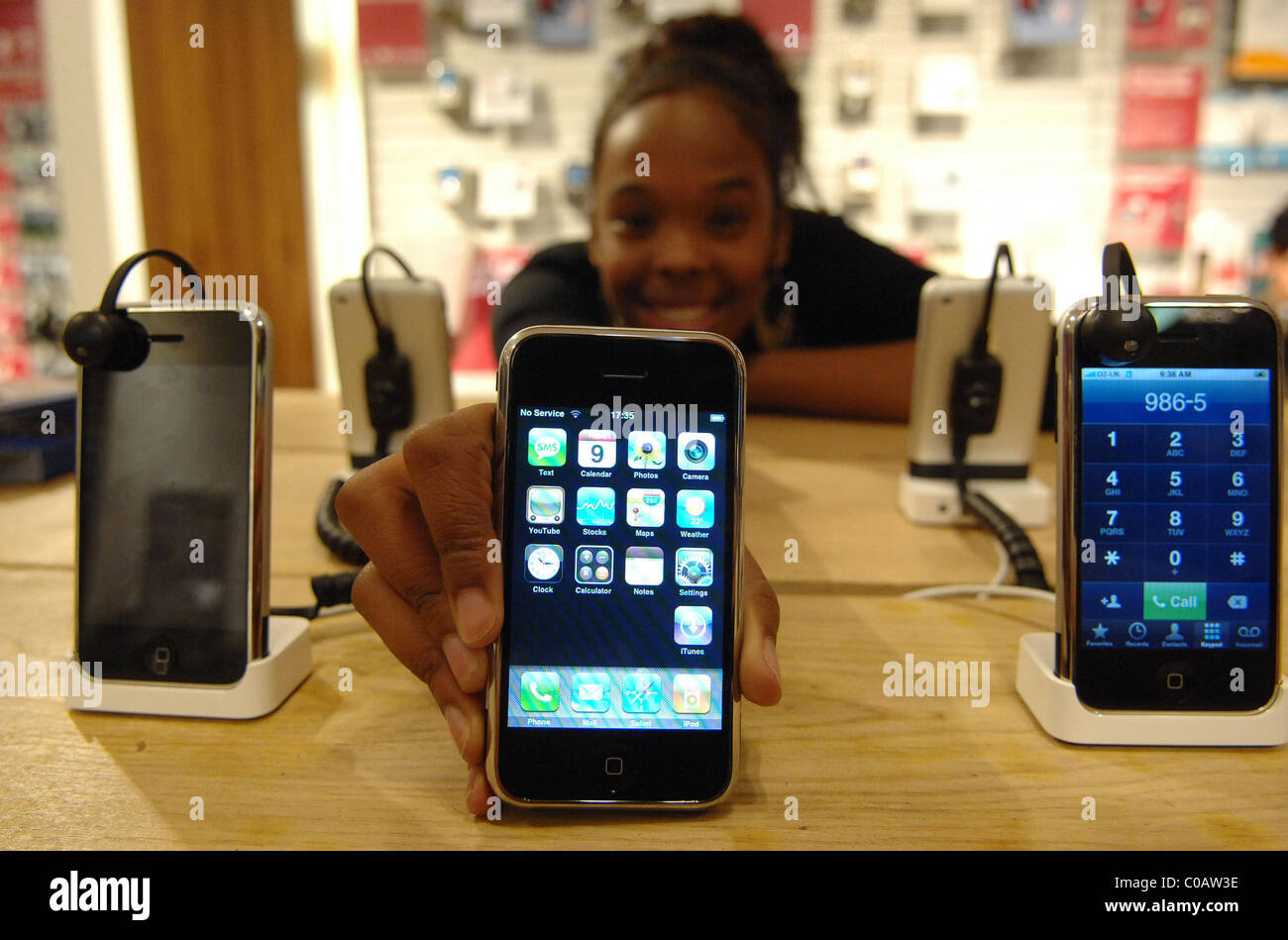 A shop assistant poses with the new Apple iPhone at the Carphone ...