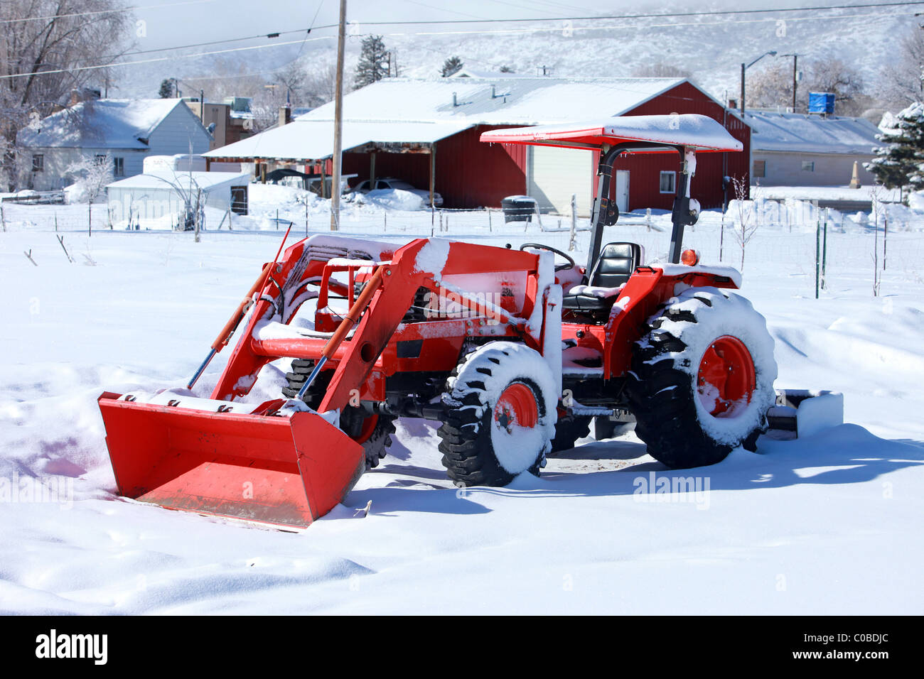 Tractor covered in snow during the winter on farm. Cold weather and ...