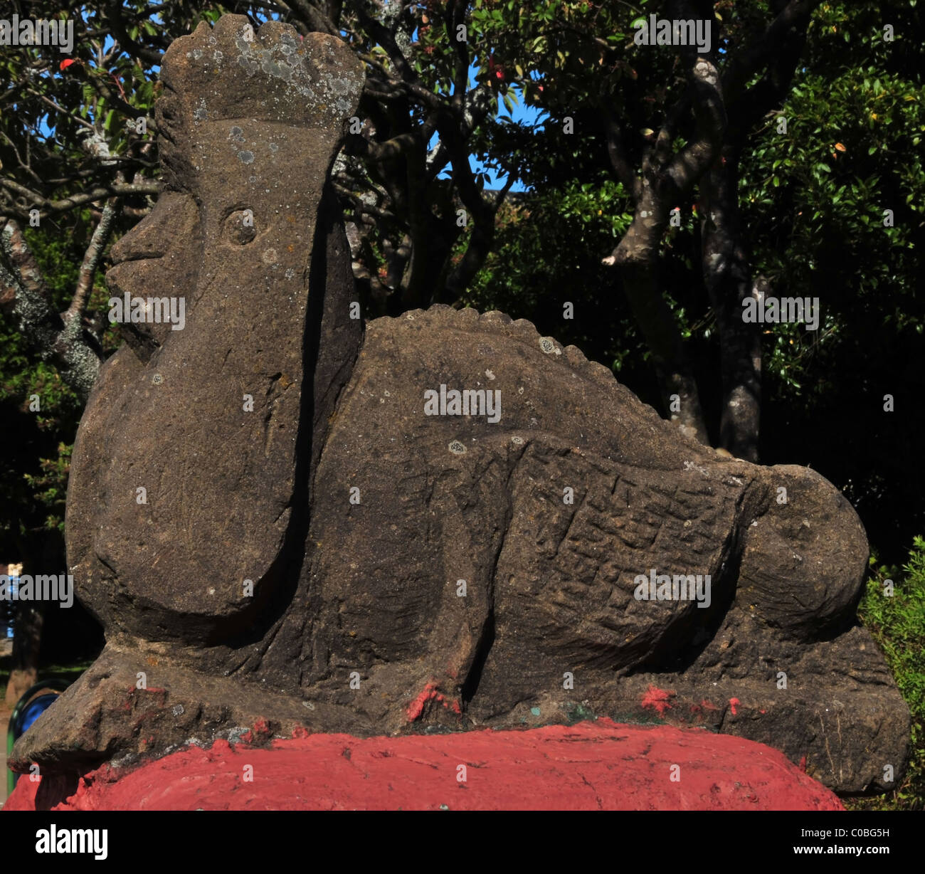 Close-up of brown effigy of Basilisco cockerel head snake, lying on red ...