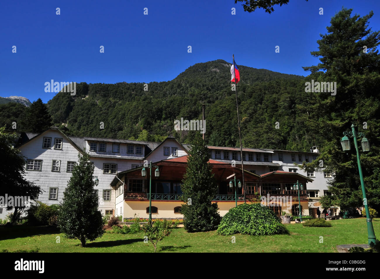 Blue sky view of the Hotel Peulla, garden greenery and Chilean Flag ...