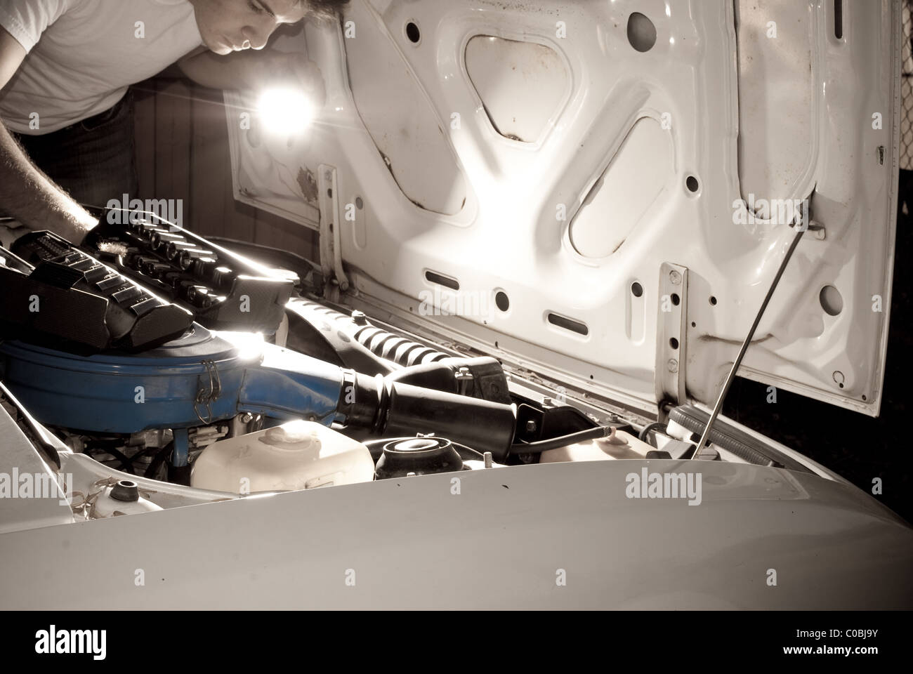 Man working on car by flashlight. Mechanic fixing auto, repair at night ...