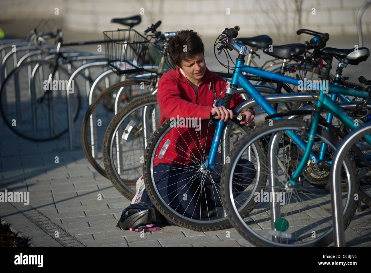 A young female degree student locking up her bicycle at a bike park on ...