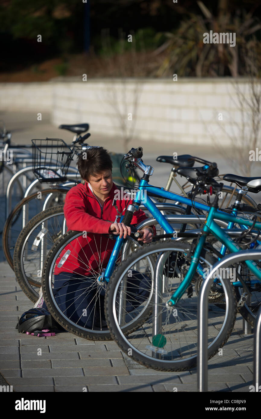 A young female degree student locking up her bicycle at a bike park on ...