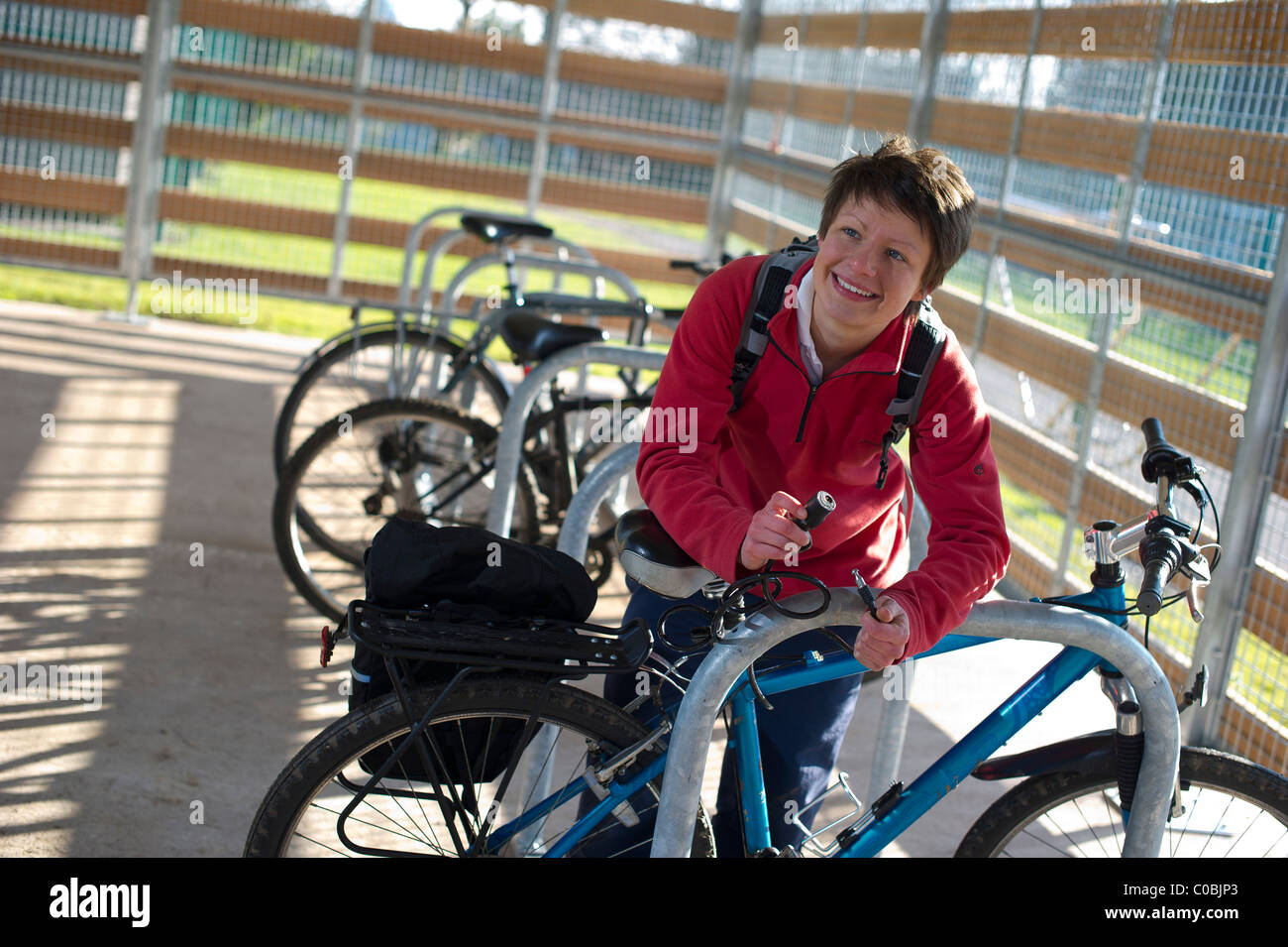 A female student cyclist locking up her bicycle in a bike park on the ...