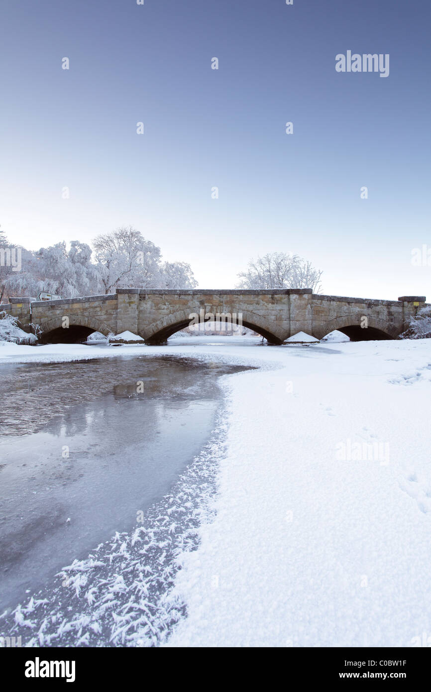 Sandstone bridge over the frozen and snow covered River Calder ...