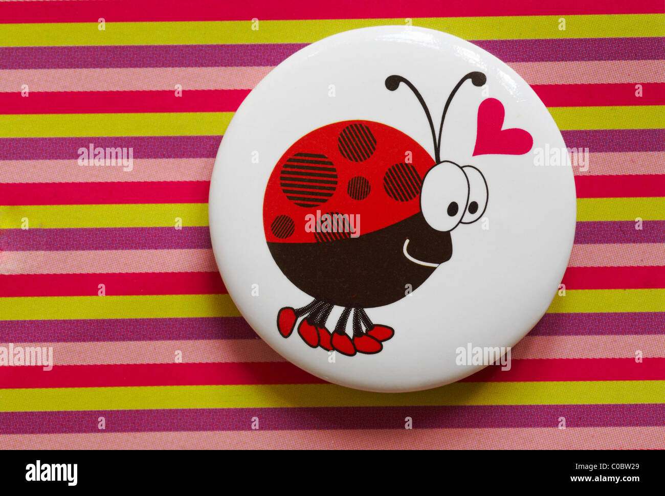 ladybird round pin badge on striped background Stock Photo - Alamy