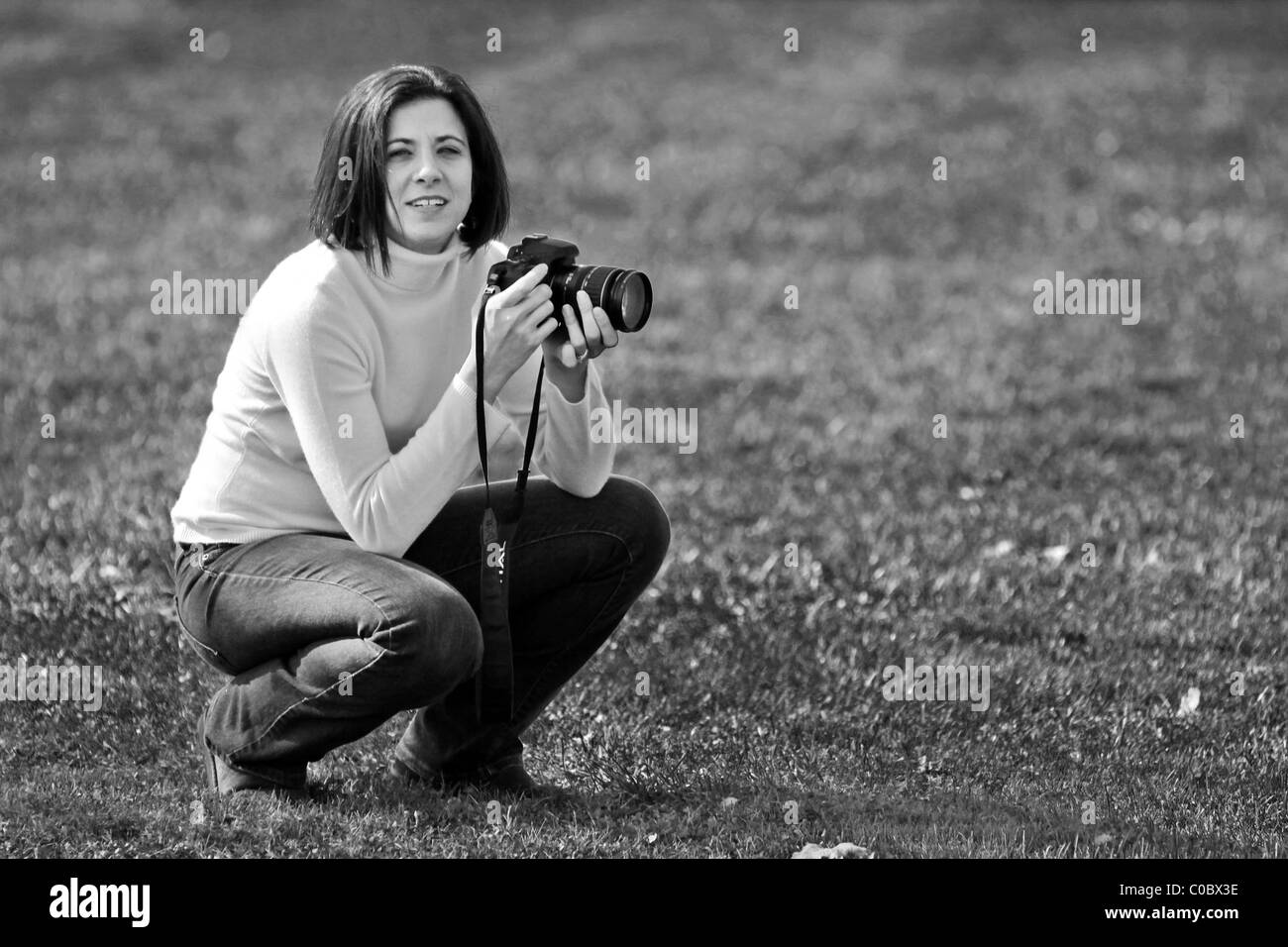 Pretty woman crouching with camera Stock Photo - Alamy