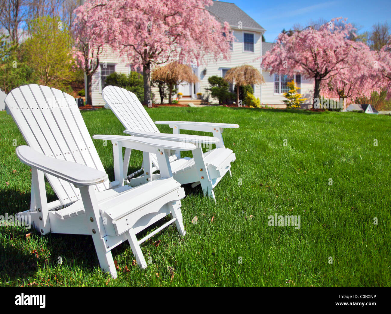 Adirondack chairs sitting on grass in front of generic colonial style ...