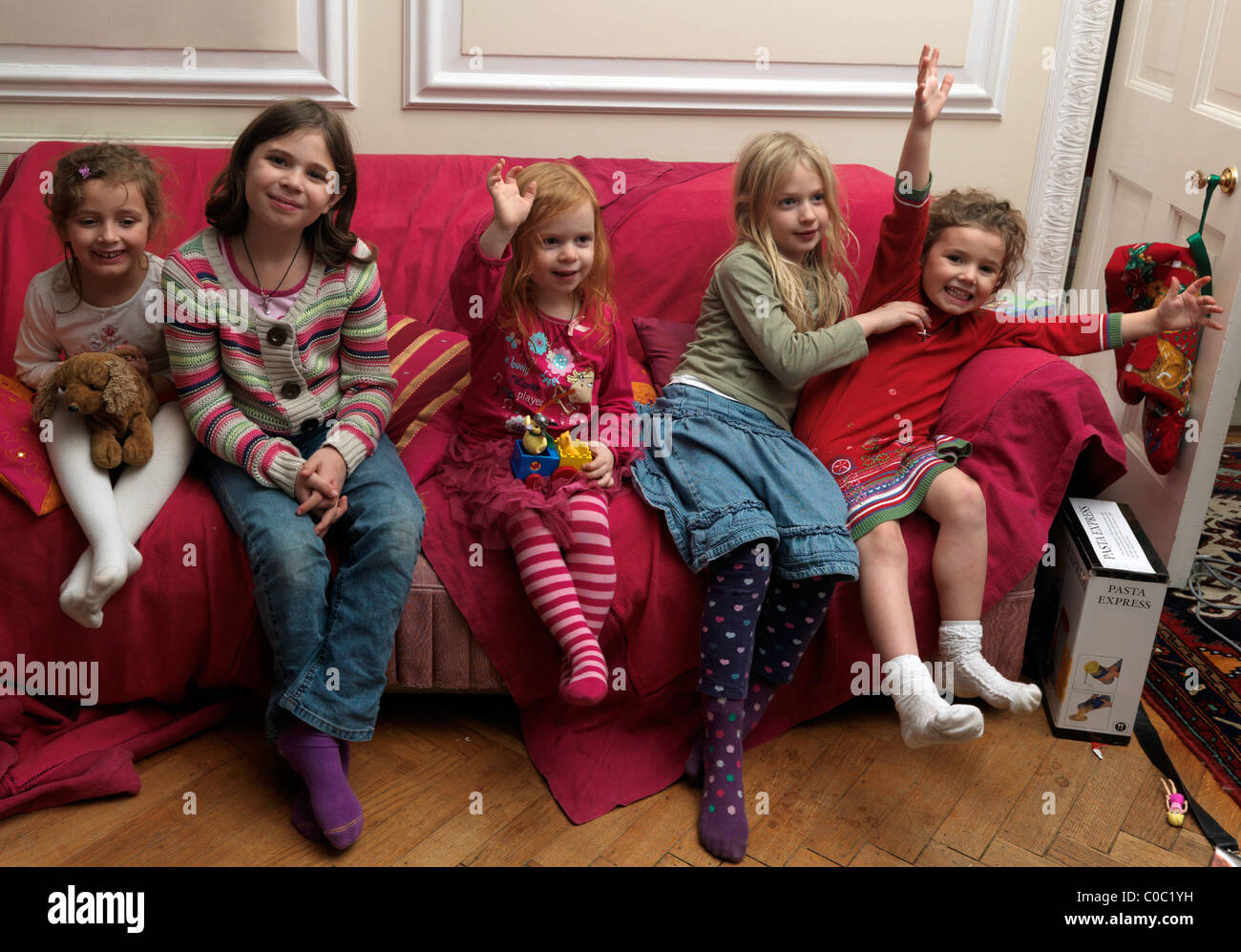 Young Sisters And Cousins Sitting On Sofa Together England Stock Photo ...