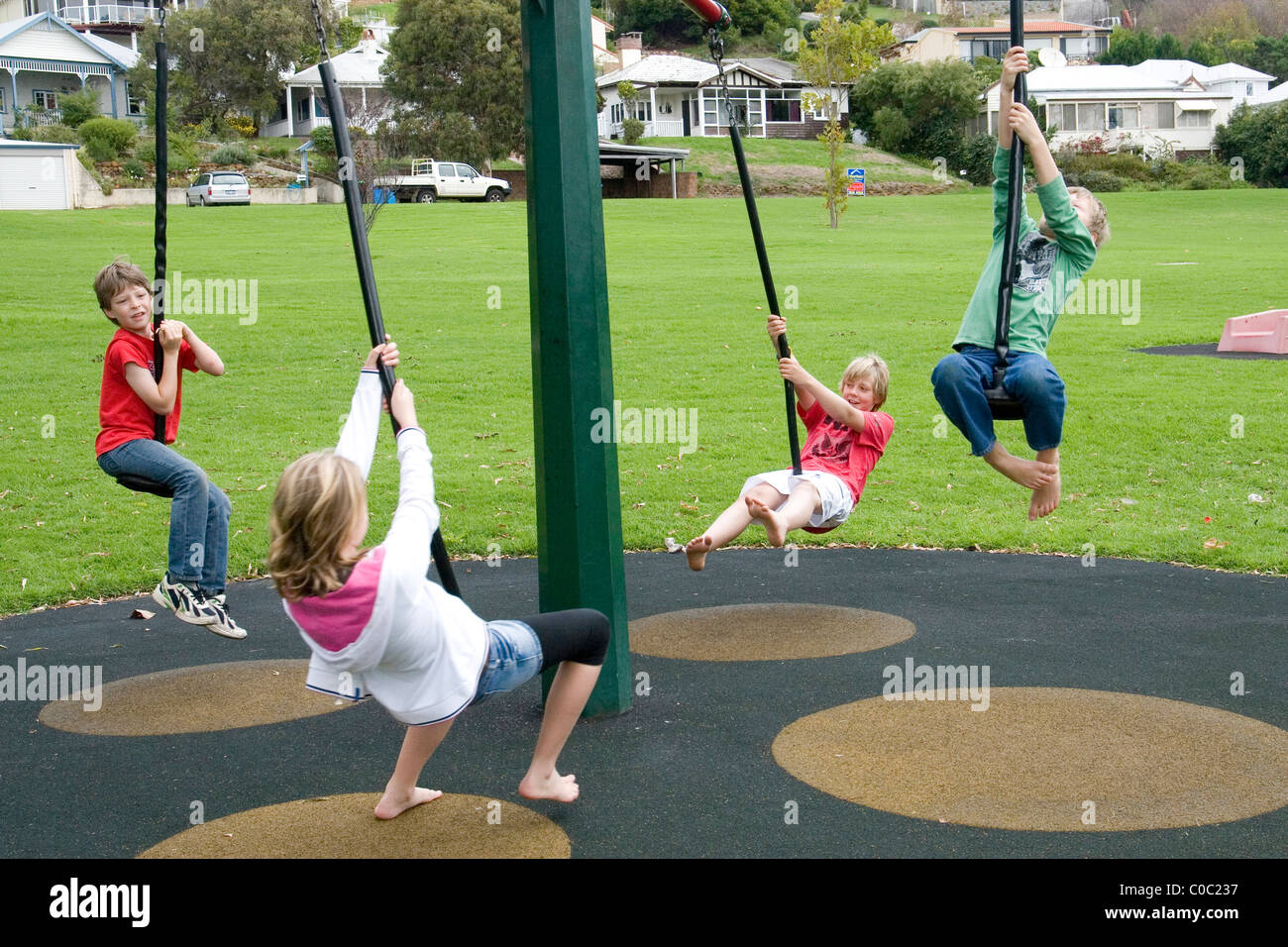 Four children playing on playground equipment Stock Photo - Alamy