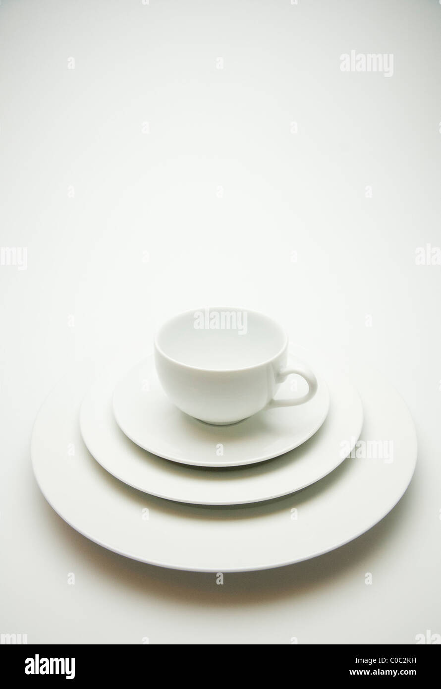Cup on stack of white dishes Stock Photo - Alamy