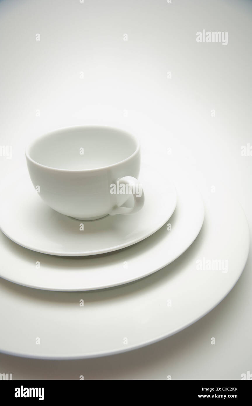 Cup on stack of white dishes Stock Photo - Alamy