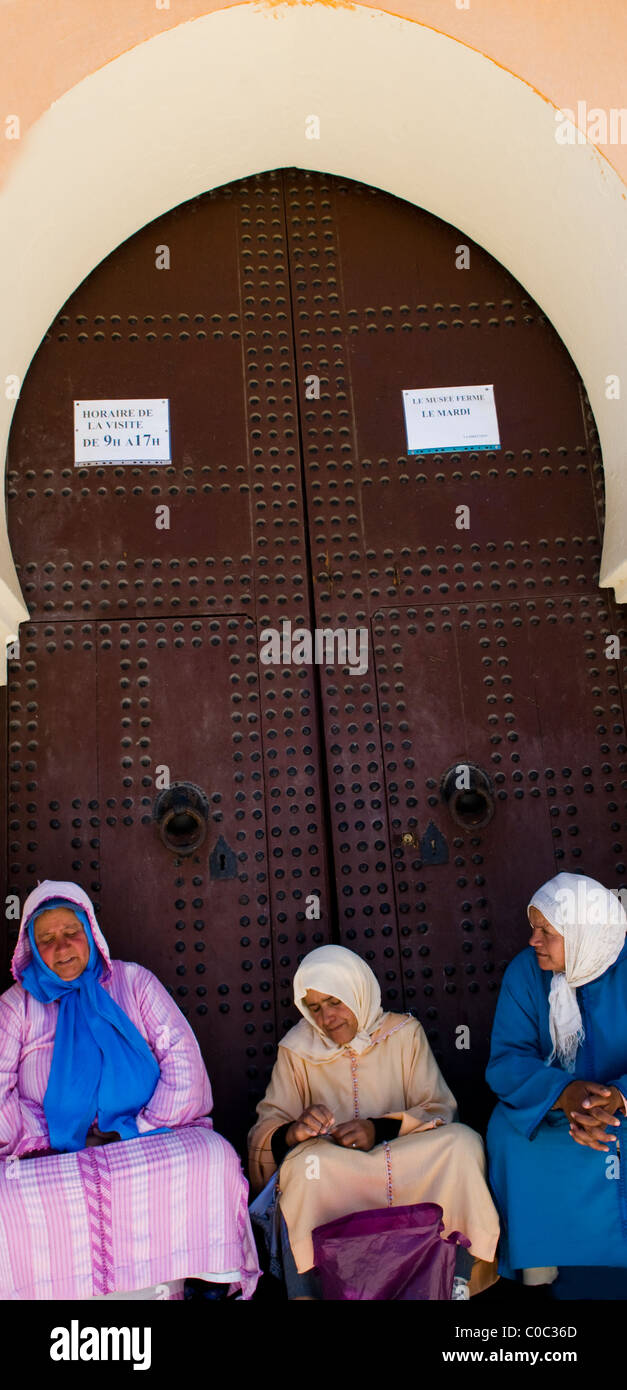 Moroccan women sitting by a colorful door in meknes Stock Photo - Alamy