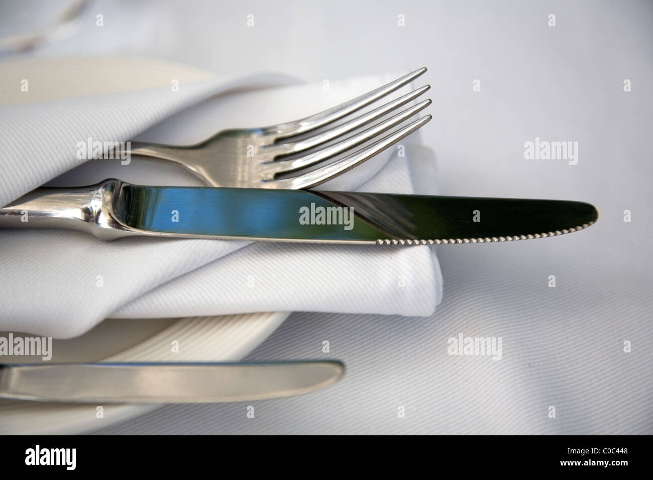 Table setting of Cutlery wrapped in cloth napkin on plate Stock Photo ...