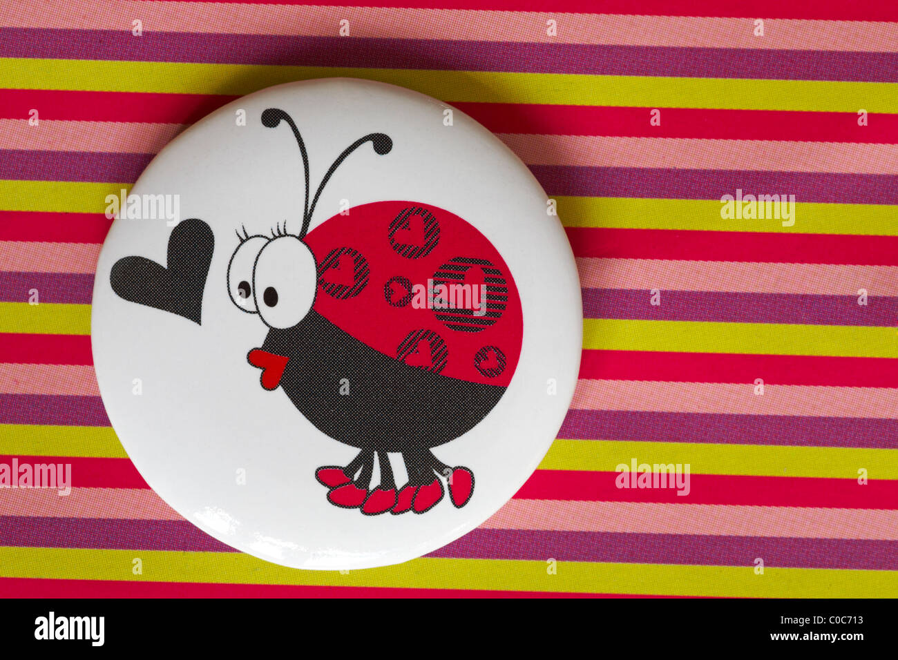 ladybird round pin badge on striped background Stock Photo - Alamy