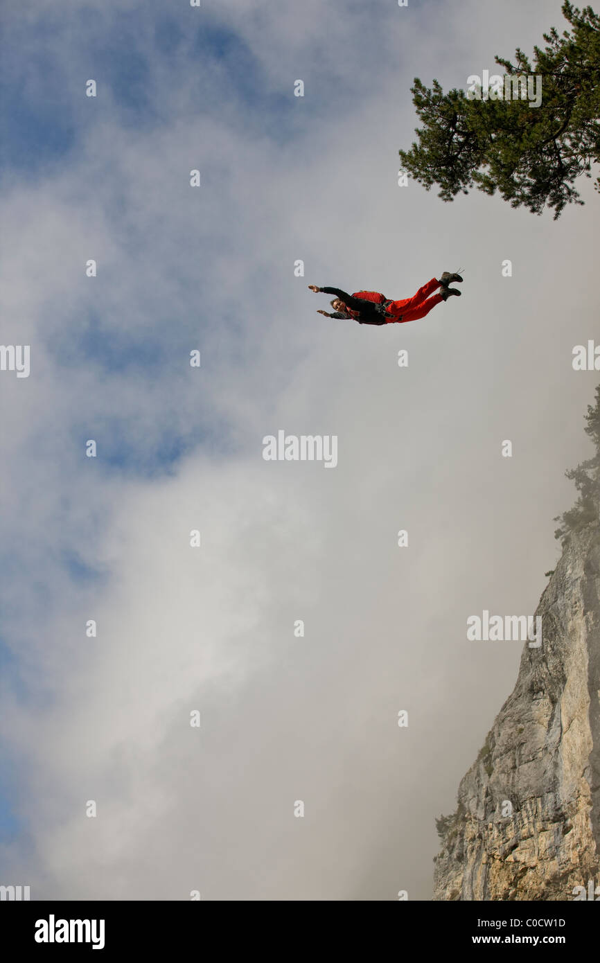 Man is jumping from cliff with BASE parachute. Thereby he is forward ...