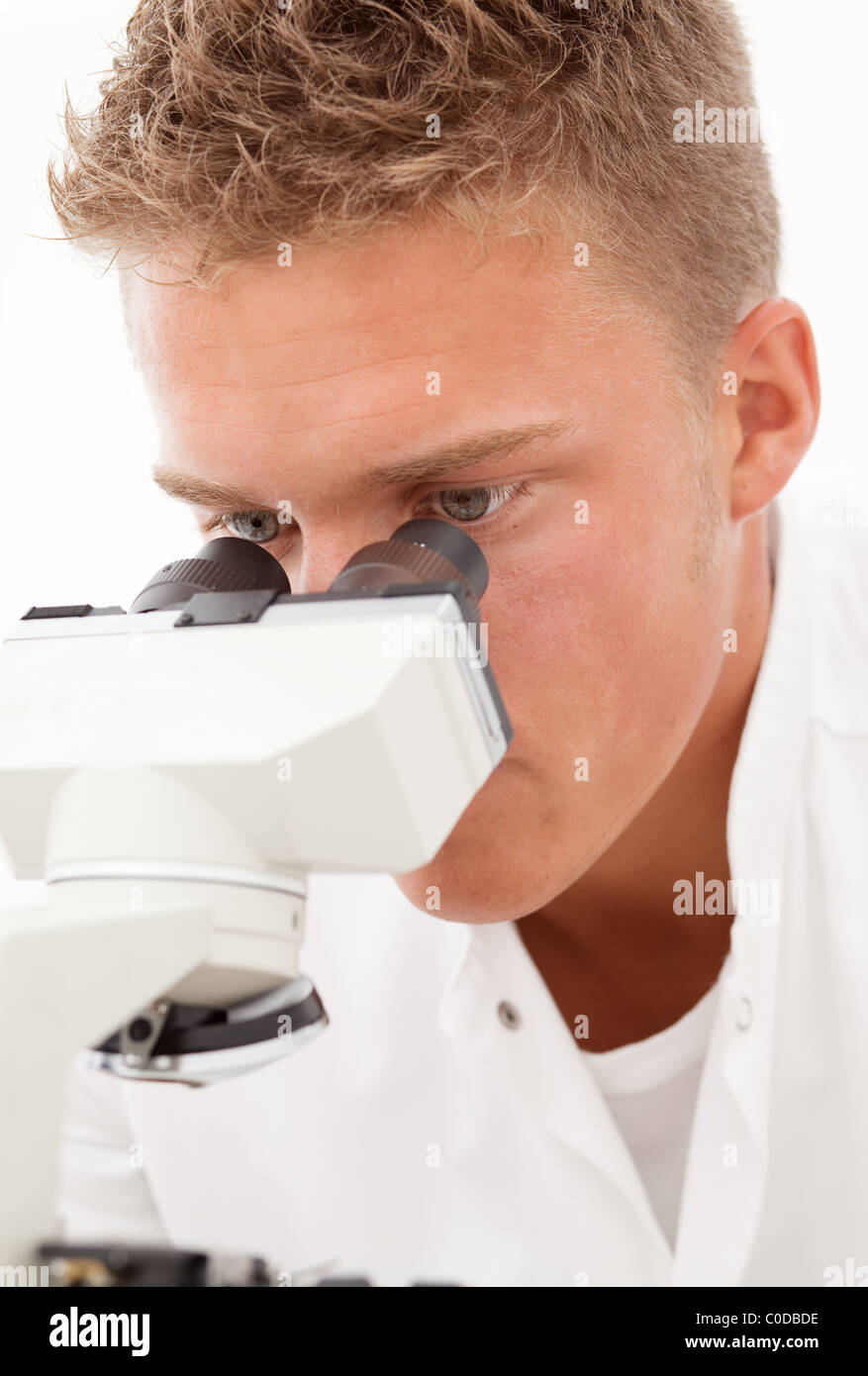 Young serious researcher inspects something in microscope Stock Photo ...