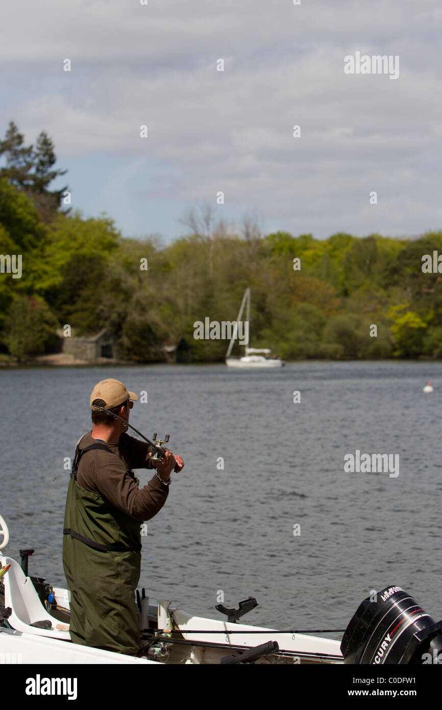 Fisherman casting with rod & line on Lake Windermere from a boat on a ...