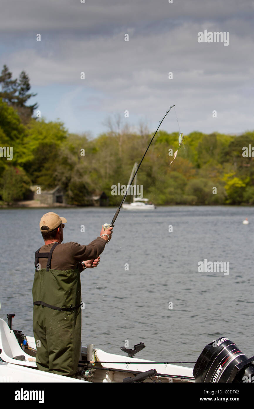 Fisherman casting with rod & line on Lake Windermere from a boat on a ...