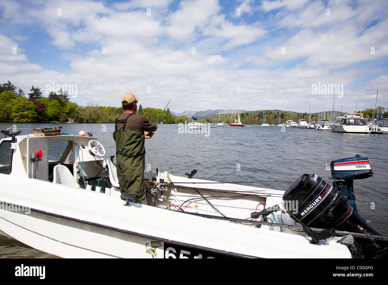 Fisherman casting with rod & line on Lake Windermere from a boat on a ...