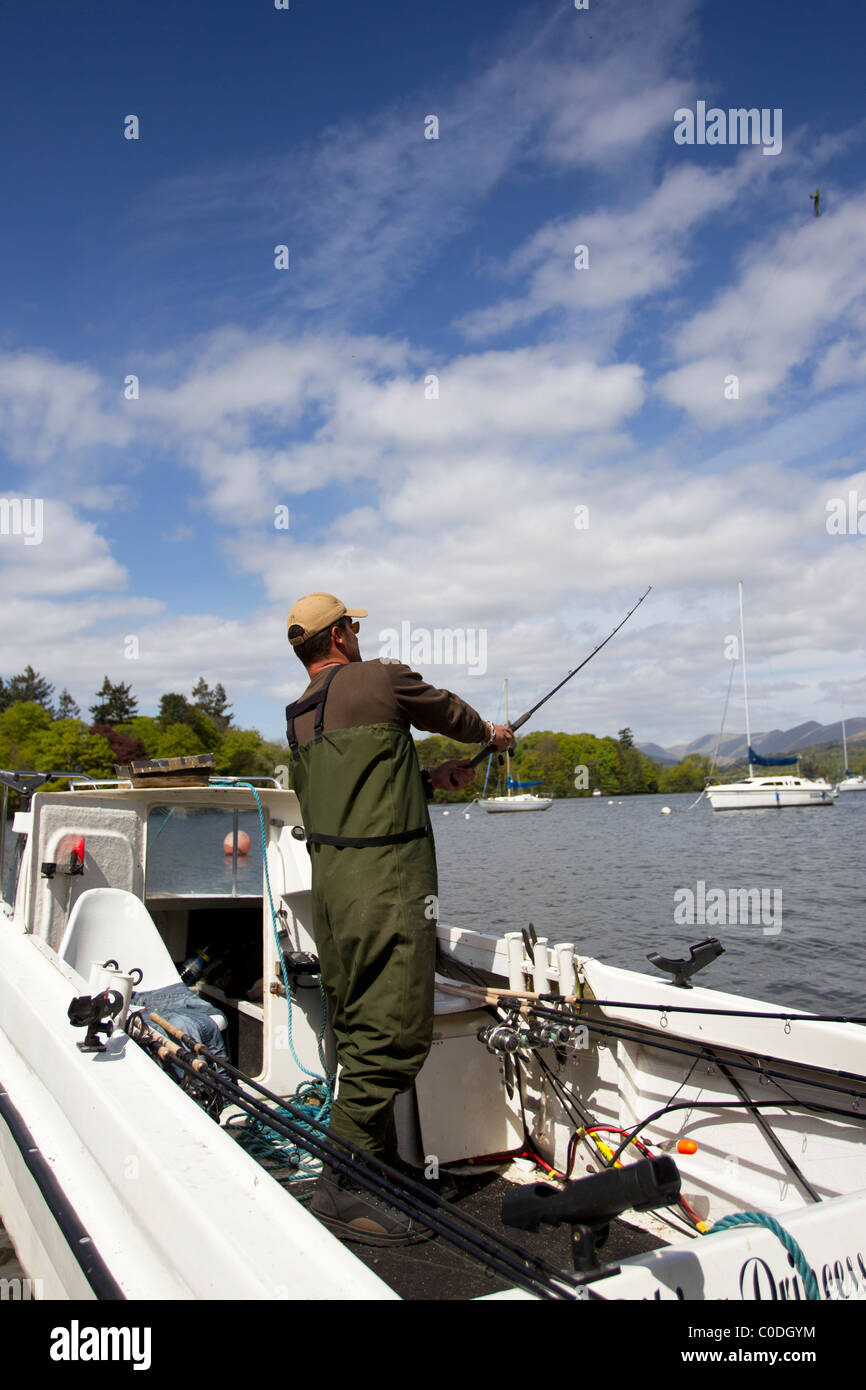 Fisherman casting with rod & line on Lake Windermere from a boat on a ...