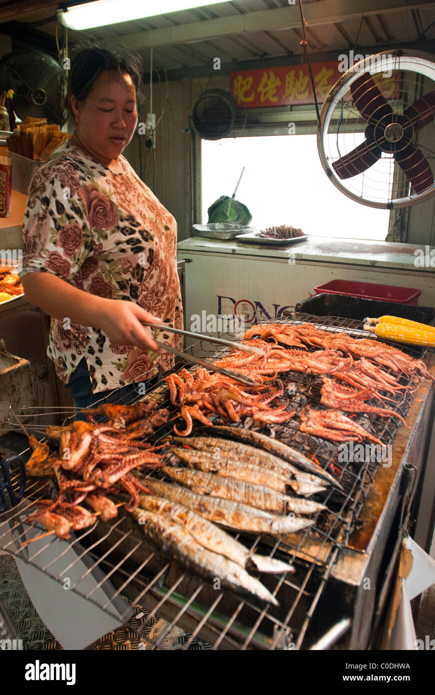 Woman working in a fish and octopus shop on the beach in Macao Stock ...