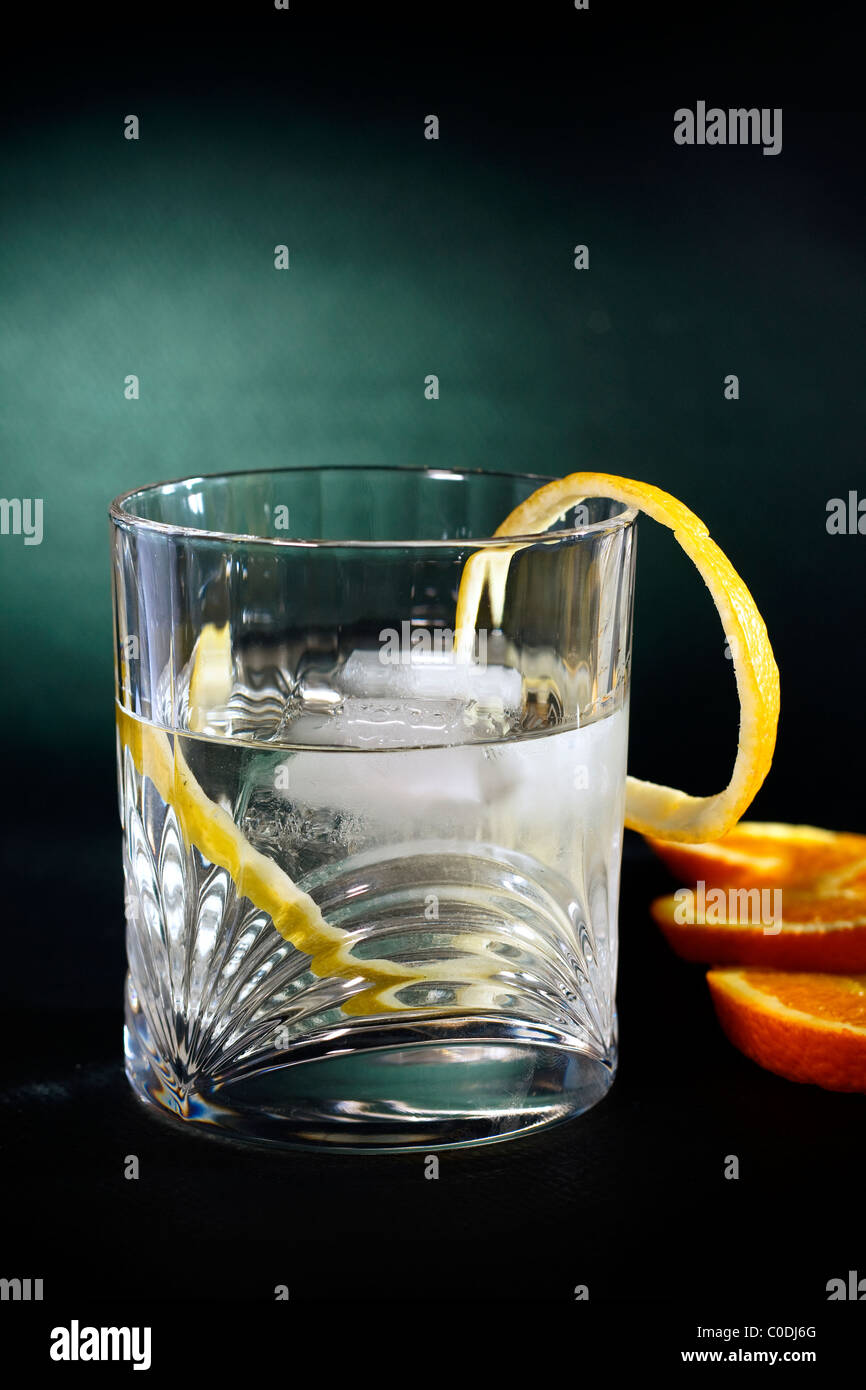 Cold vodka in a glass, with decor oranges and lemon, in black green ...