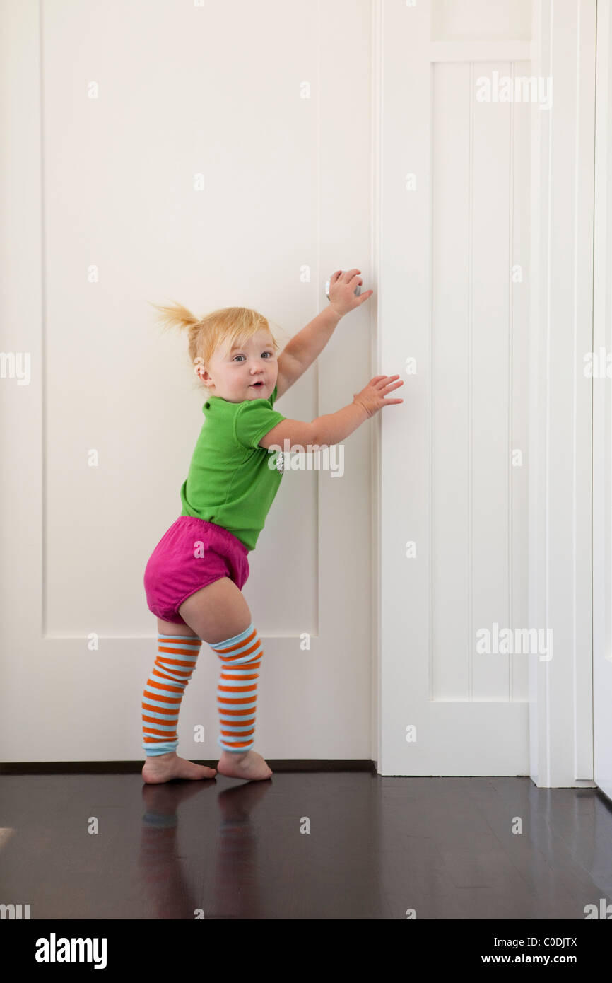 Little girl trying to get in closed door Stock Photo - Alamy